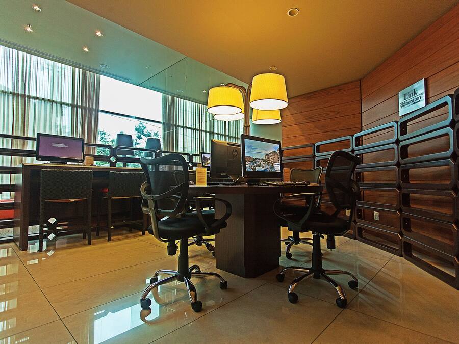 Um espaço de escritório moderno com duas mesas, cadeiras e uma grande janela com cortinas.