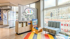 Espaço infantil com área de recreação, um sofá e vista para a rua.