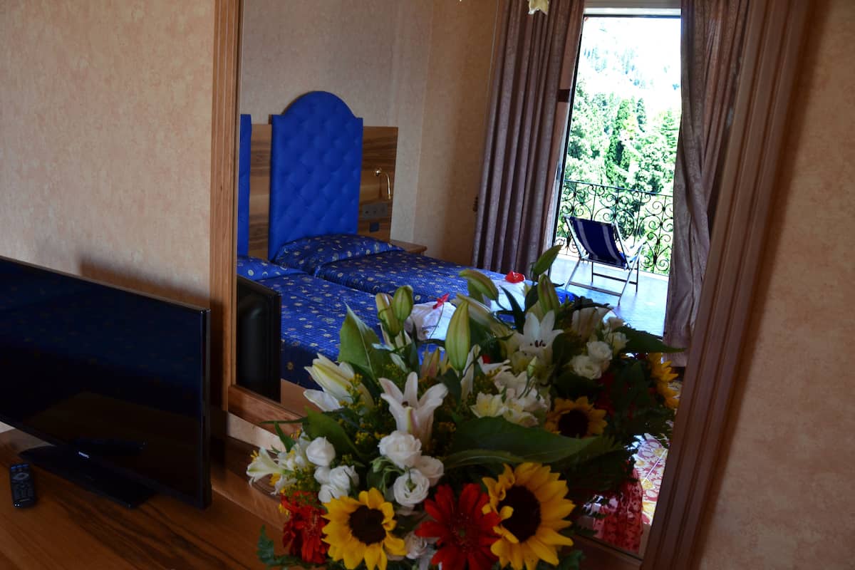 Quarto com cama, televisão e varanda com cadeira.