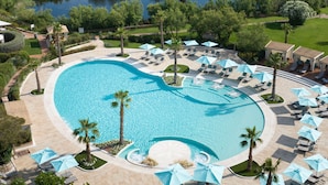 Um resort com uma piscina grande, espreguiçadeiras e vista para o mar.