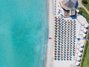 Praia particular, areia branca, espreguiçadeiras, guarda-sóis 