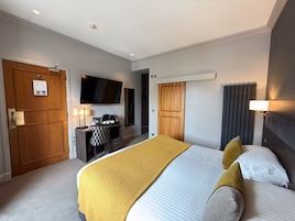 Quarto de hotel com uma cama, uma escrivaninha, uma televisão de tela plana e uma porta.