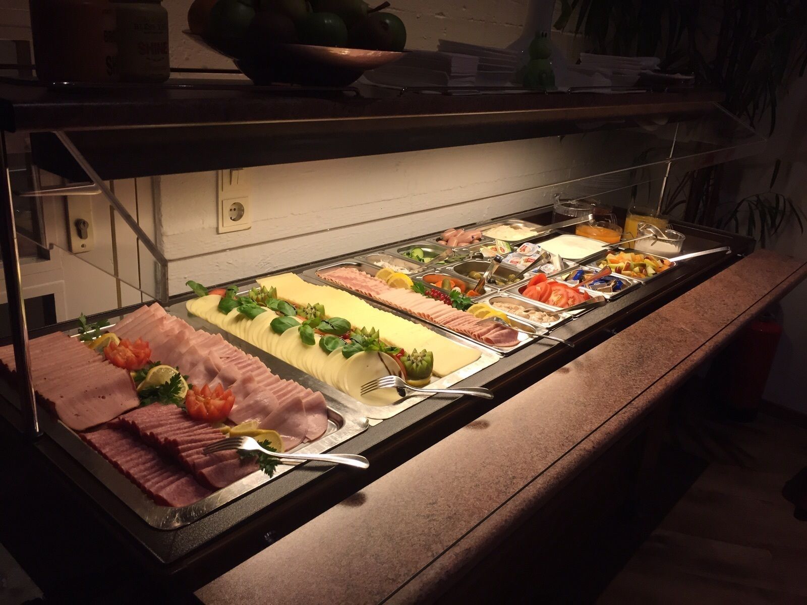 Buffet com diversas opções de comida, incluindo carnes, queijos e vegetais.