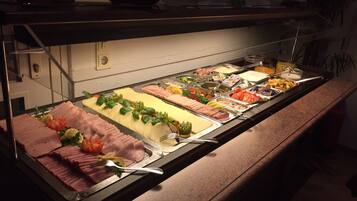 Buffet com diversas opções de comida, incluindo carnes, queijos e vegetais.