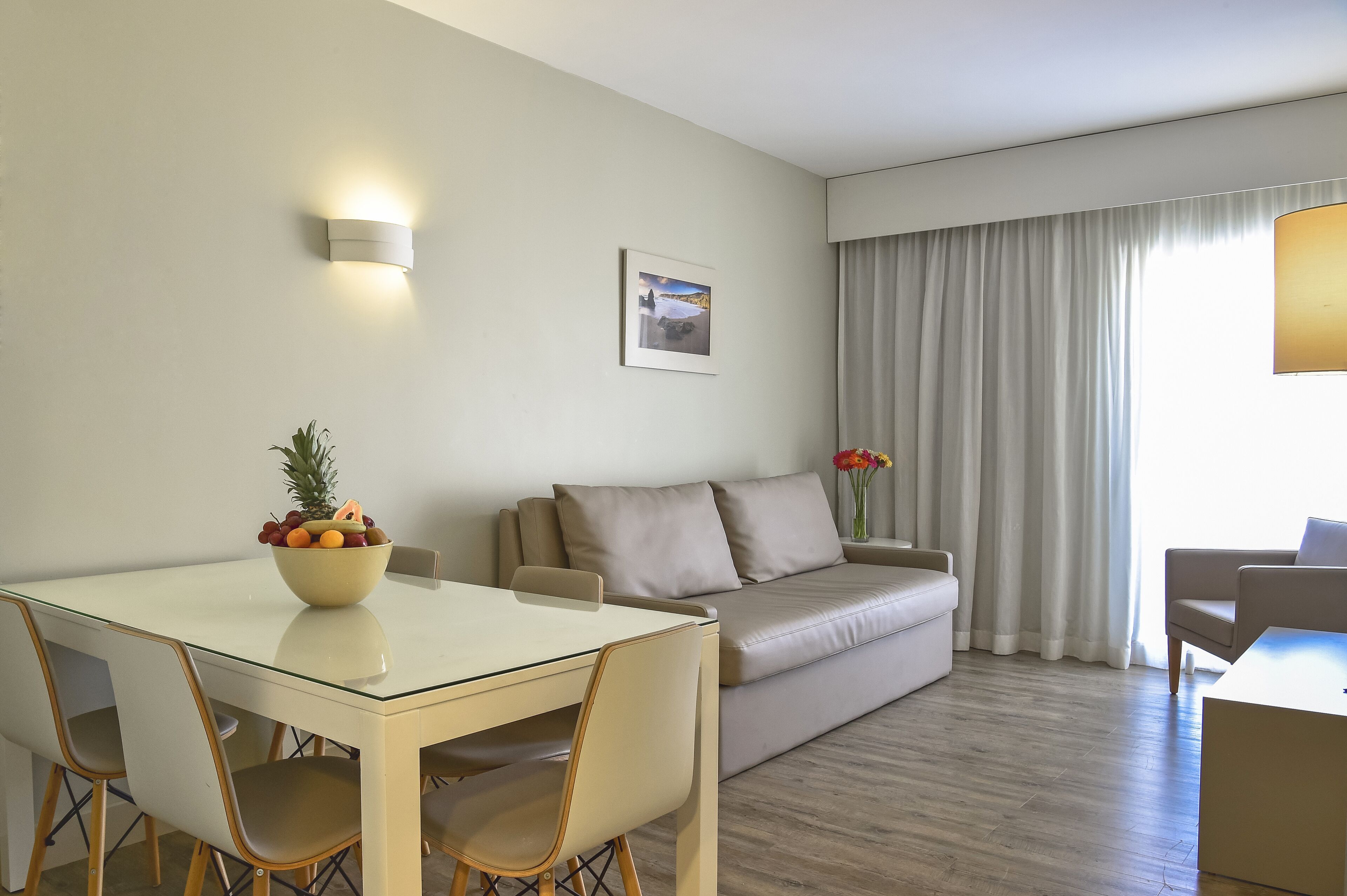 Quarto de hotel moderno com mesa de jantar, sofá e mesa de centro.