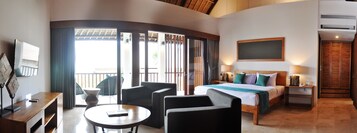 Quarto de hotel com cama, escrivaninha, cadeira, mesa e varanda com cortinas.