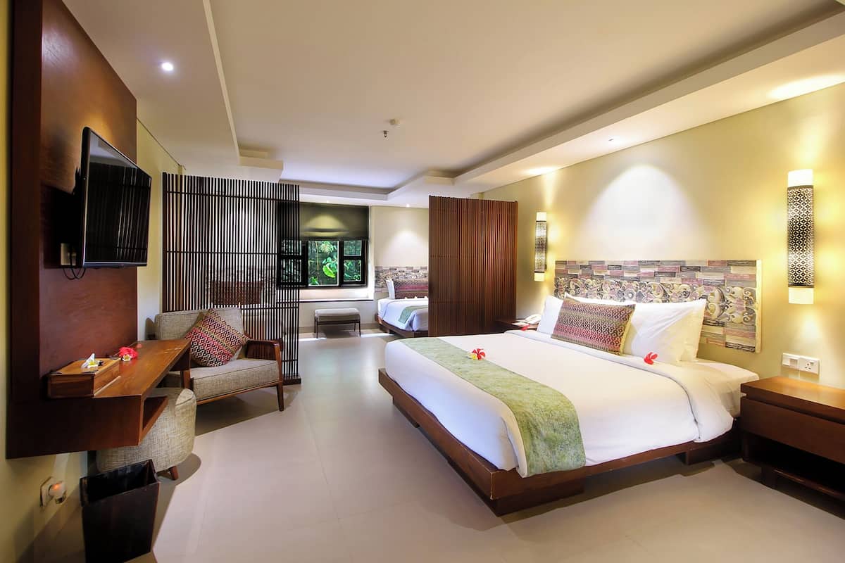 Quarto de hotel moderno com uma cama grande, escrivaninha, televisão e vista para o exterior.