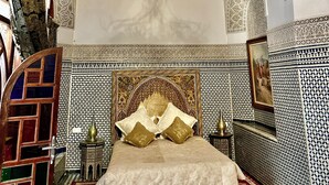 Quarto com uma cama grande, teto ricamente decorado e paredes com padrão.