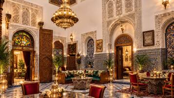 Um interior luxuoso com trabalhos em azulejos ornamentados, um imponente candelabro e áreas de estar acolhedoras.