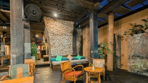 Um interior aconchegante com parede de pedra, móveis de madeira e um ventilador.
