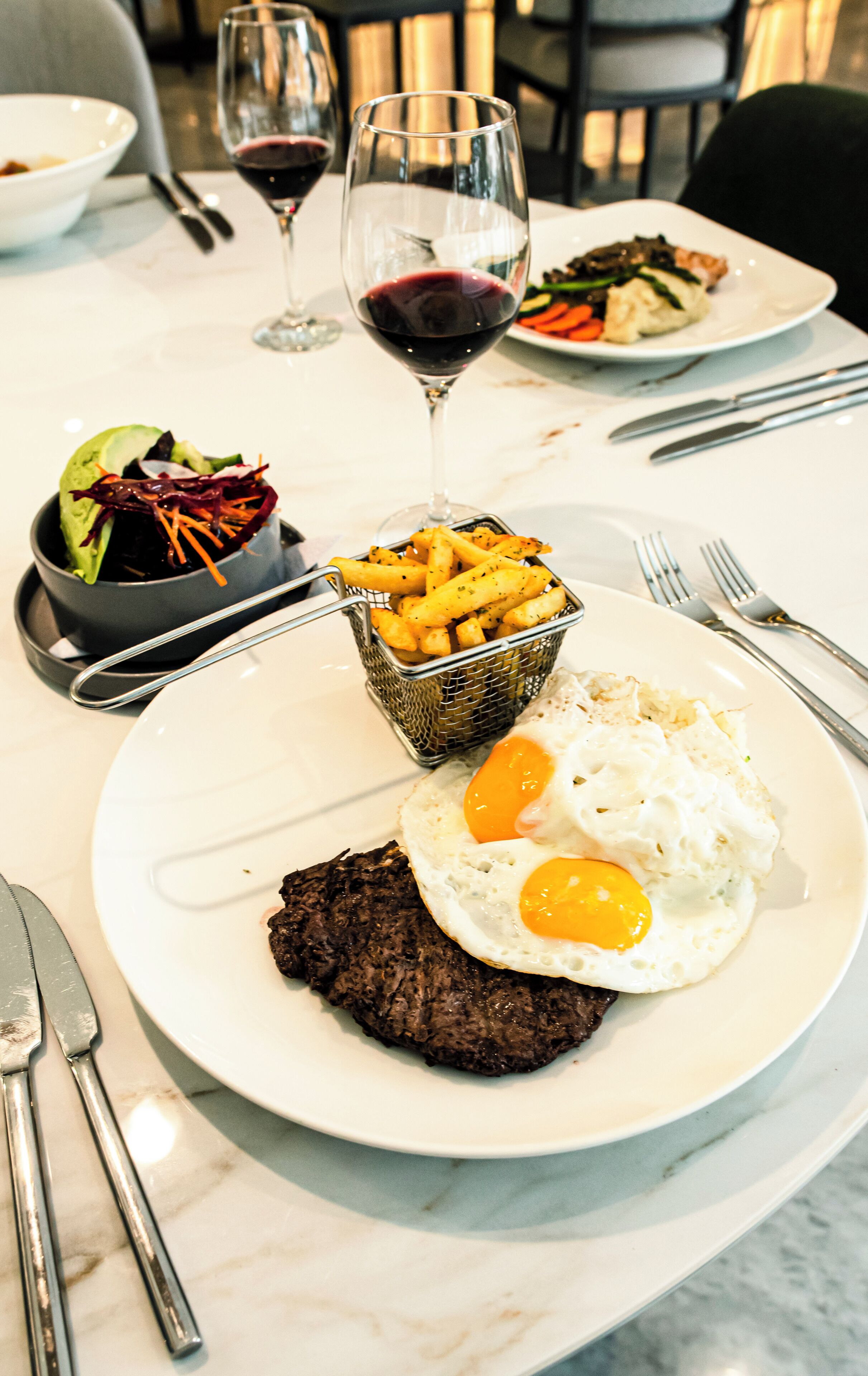 Um prato com bife, ovos fritos e batatas fritas.