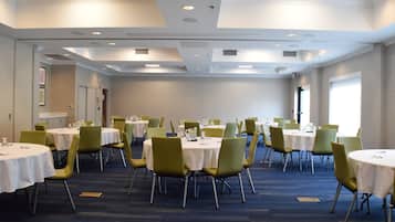 Uma sala de conferências com várias mesas redondas e cadeiras, dispostas em fileiras.