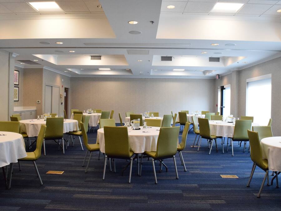 Uma sala de conferências com várias mesas redondas e cadeiras, dispostas em fileiras.