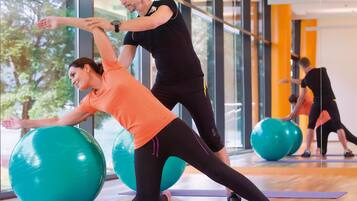 Aula de fitness com participantes usando bolas de exercício em sala bem iluminada, com grandes janelas.