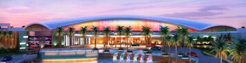 Exterior do Desert Diamond West Valley Resort, com uma entrada grande e curva, palmeiras e uma piscina refletora.