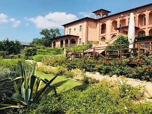 Um edifício grande com várias arcadas e um jardim com diversas plantas e flores.