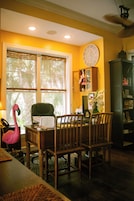 Uma sala de jantar com uma mesa de madeira, cadeiras, um relógio e uma janela com persianas.