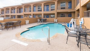 Um hotel com piscina, área de estar externa e um edifício de vários andares com varandas.