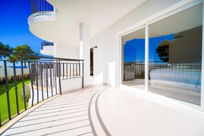 Um edifício moderno com varanda curva, amplas janelas de vidro e vista para o mar.