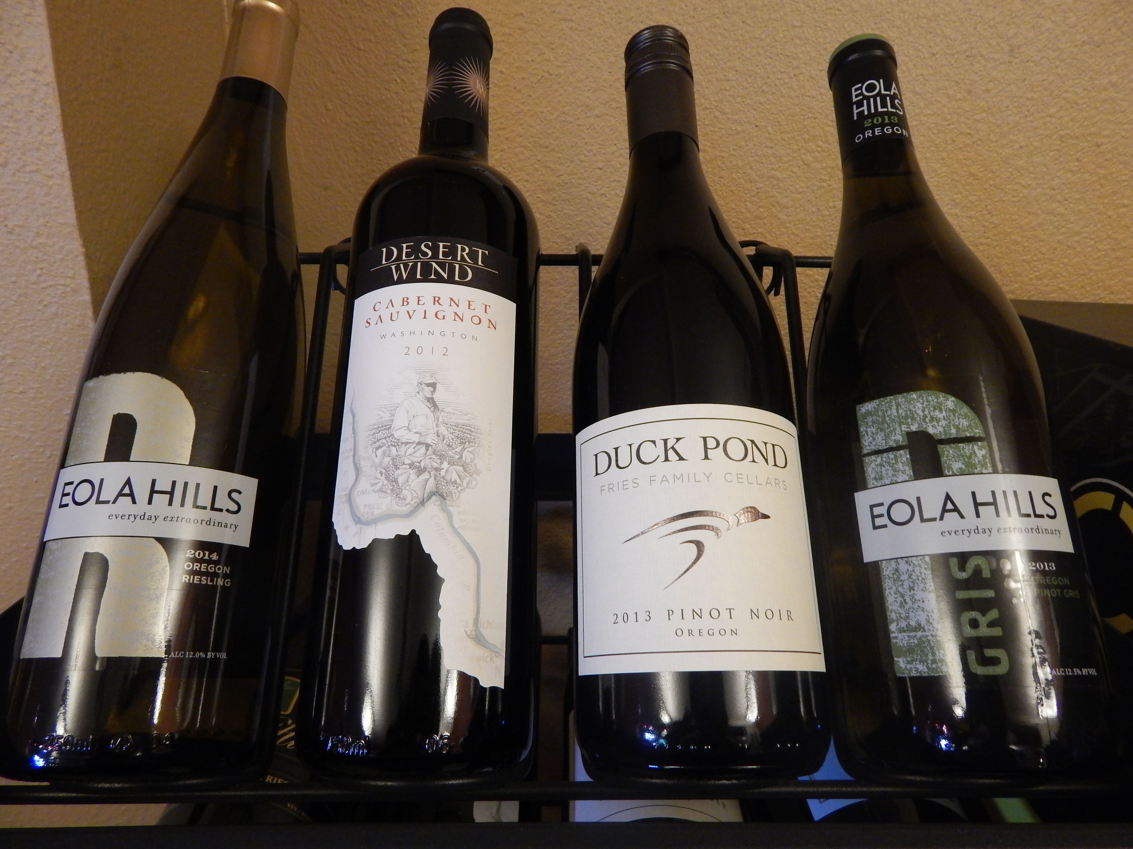 Quatro garrafas de vinho em uma estante.