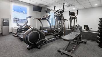 Academia com máquinas de cardio, equipamentos de musculação e um bebedouro.