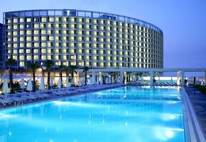 Um hotel com um edifício grande e curvo, piscina e espreguiçadeiras.