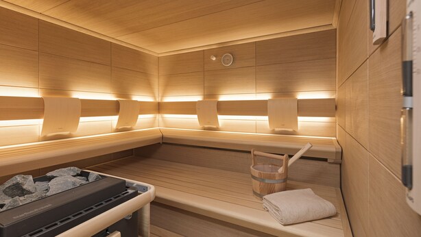 Uma sauna com bancos de madeira, um porta-toalhas e um balde de pedras.