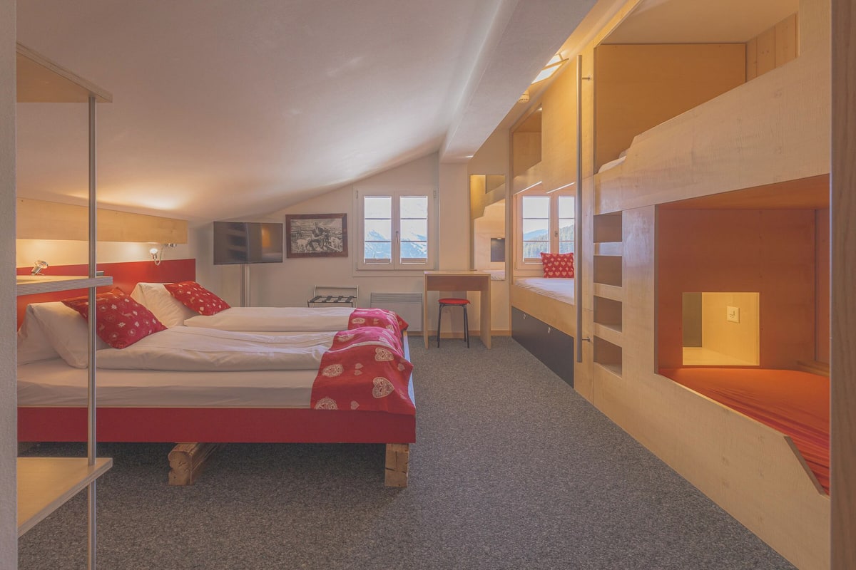 Quarto compacto com cama beliche, escrivaninha e cadeira.