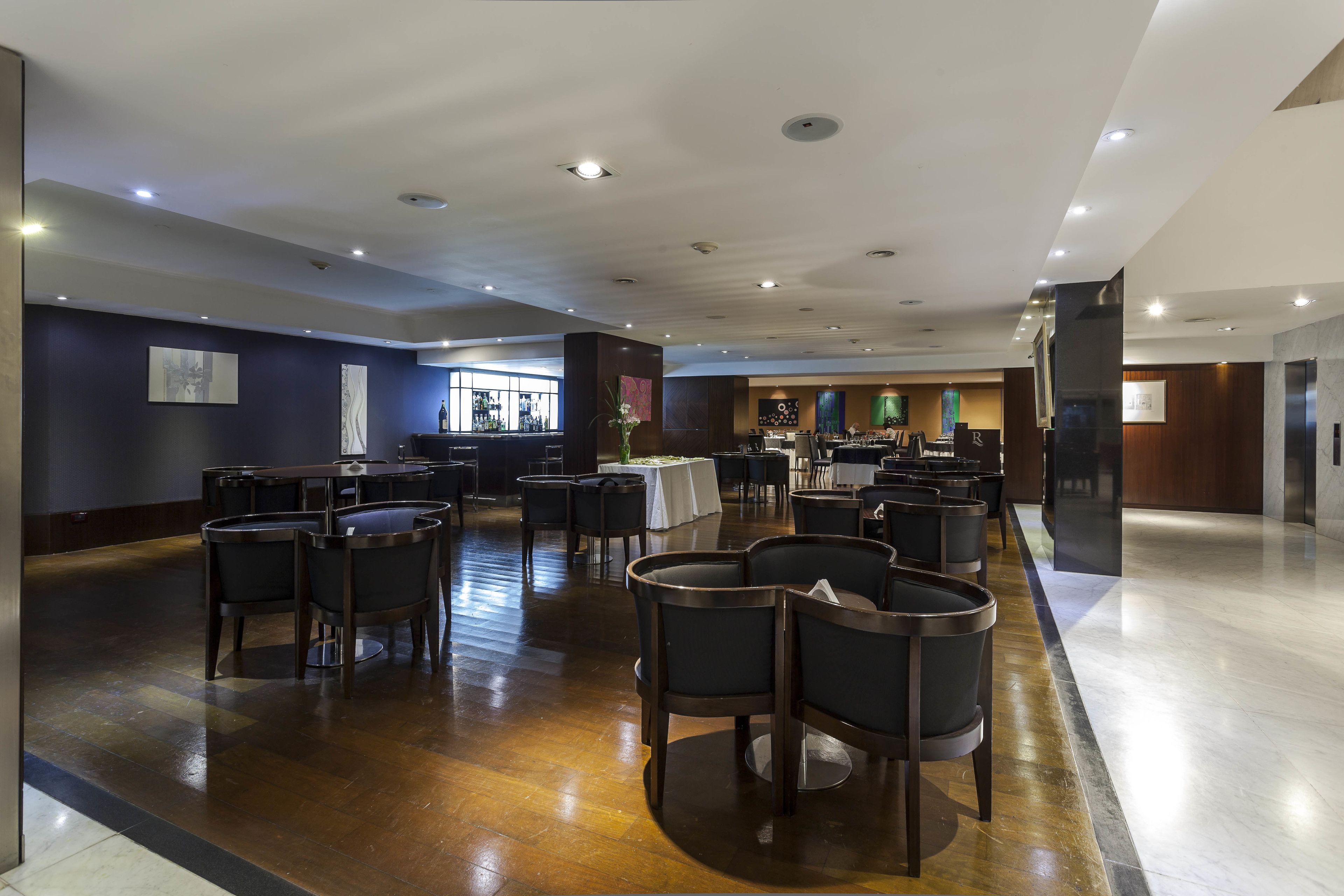 Um hall amplo com área de bar, diversos assentos e piso de madeira polida.