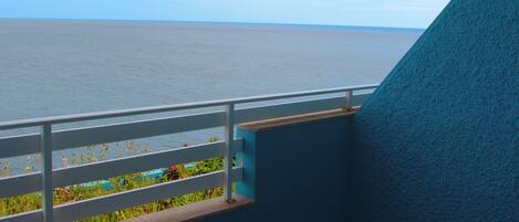 Varanda com vista para o mar, um corrimão e uma parede azul.