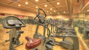 Uma academia com diversos equipamentos de ginástica cardiovascular, incluindo esteiras e elípticos, dispostos em fileiras.
