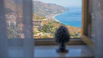 Vista costeira de uma janela com vista para uma praia e uma cidade em colinas.