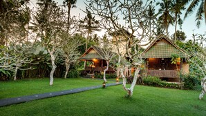 Um resort tropical com duas villas de madeira cercadas por vegetação exuberante e palmeiras.