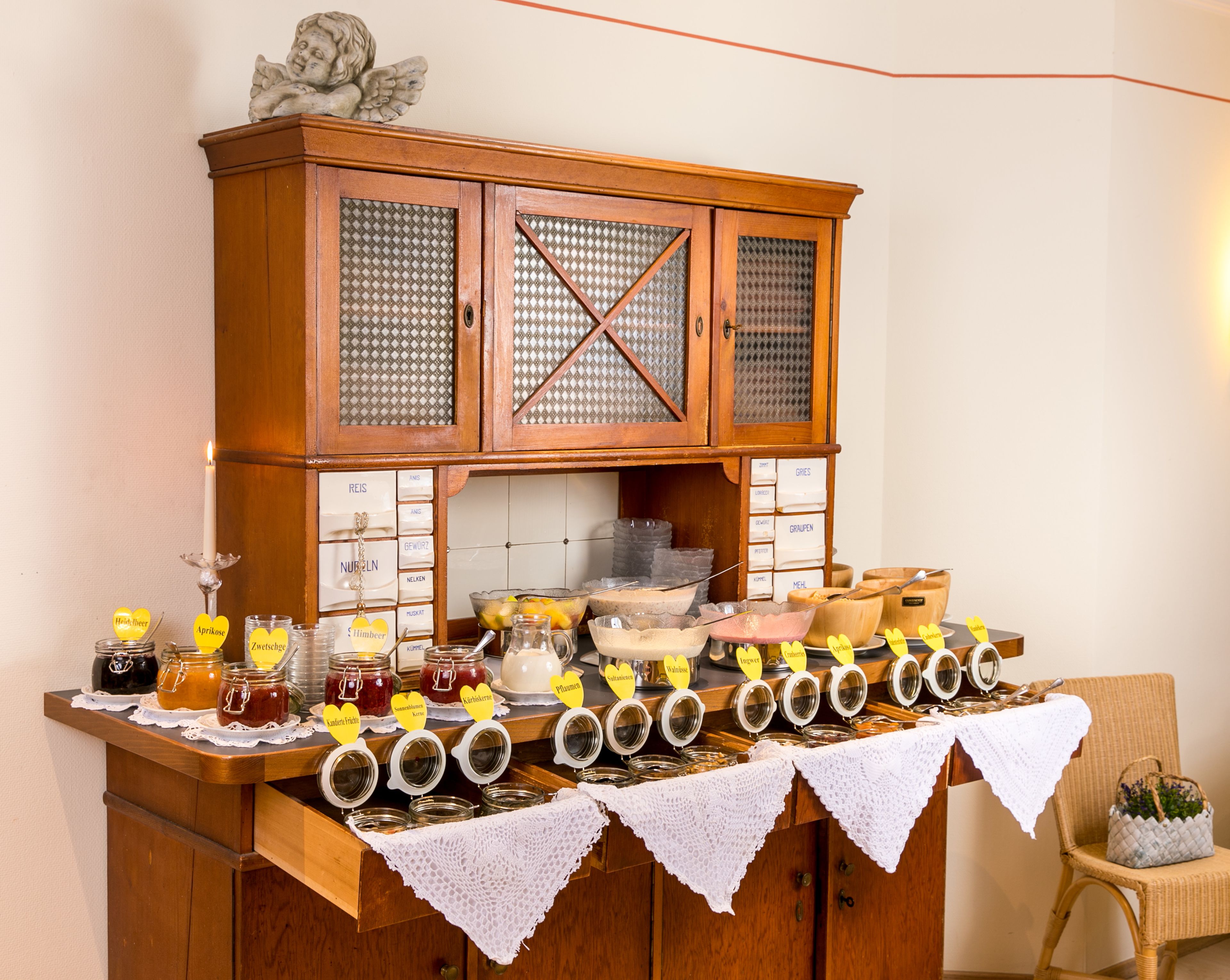 Uma mesa de buffet de madeira com diversos alimentos e potes rotulados em alemão.