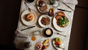 Mesa de café da manhã com diversos pratos, incluindo torradas, ovos e frutas.
