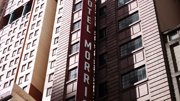 Um edifício alto com uma placa vertical chamativa que diz "HOTEL MORRIS".