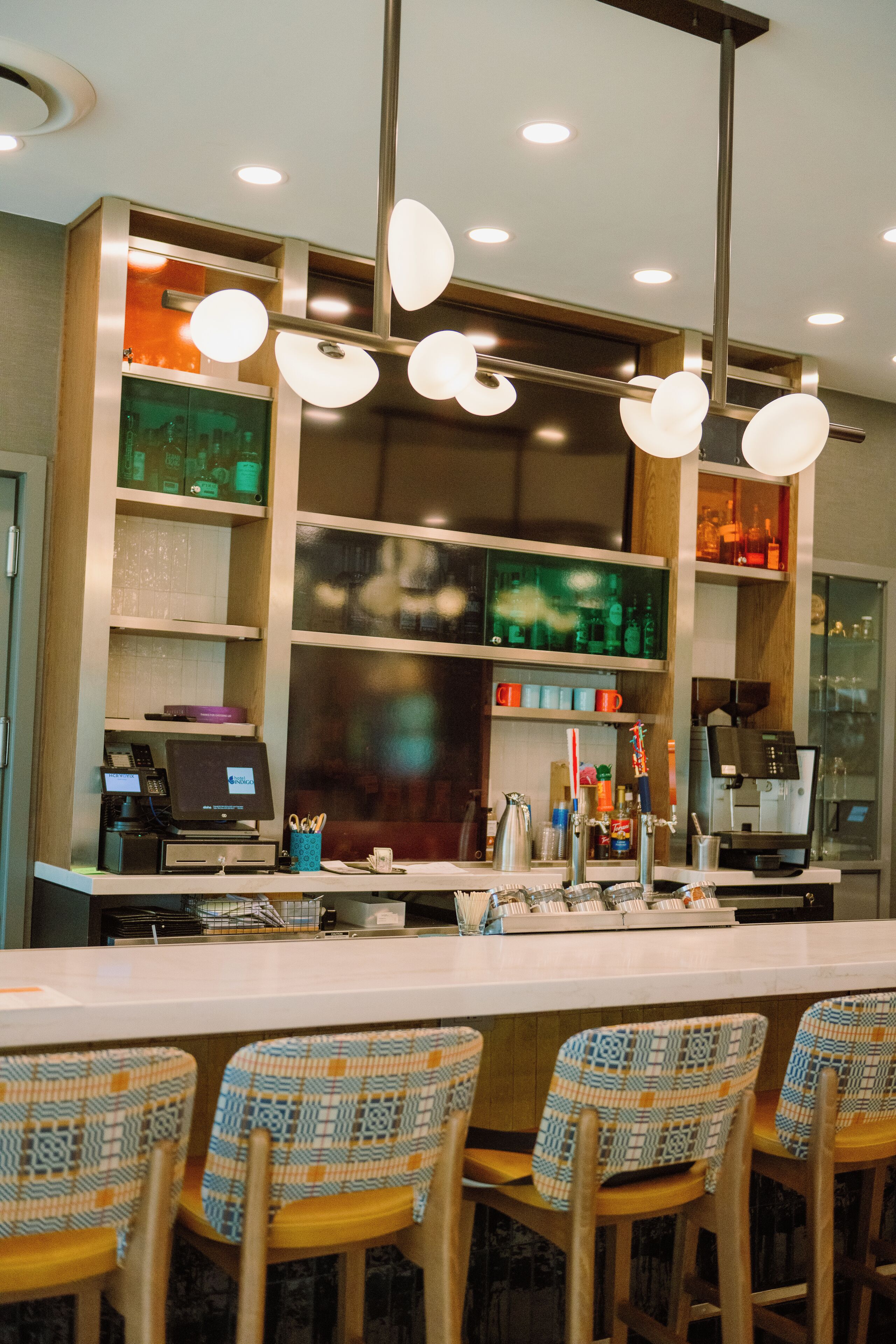 Uma área de bar moderna com um balcão comprido, banquetas e uma máquina de café.