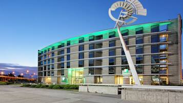 Um edifício moderno com uma escultura espiral marcante na frente, grandes janelas e a placa Holiday Inn.