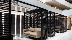 Um interior moderno com um sofá, uma mesa de centro de vidro e um separador com ripas horizontais.