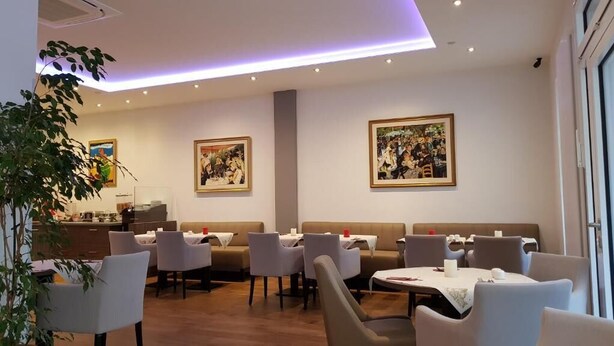 Um restaurante com mesas, cadeiras, balcão e quadros nas paredes.