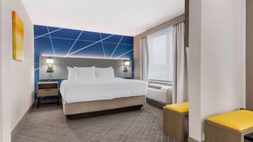 Quarto de hotel com cama, mesas de cabeceira, luminária na parede, janela com cortinas e piso estampado.