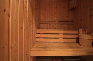 Uma sauna de madeira com bancos e um balde.