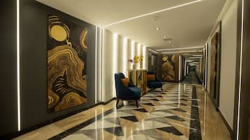 Um corredor de hotel moderno com piso estampado em padrão geométrico, obras de arte fixadas na parede e iluminação suave.
