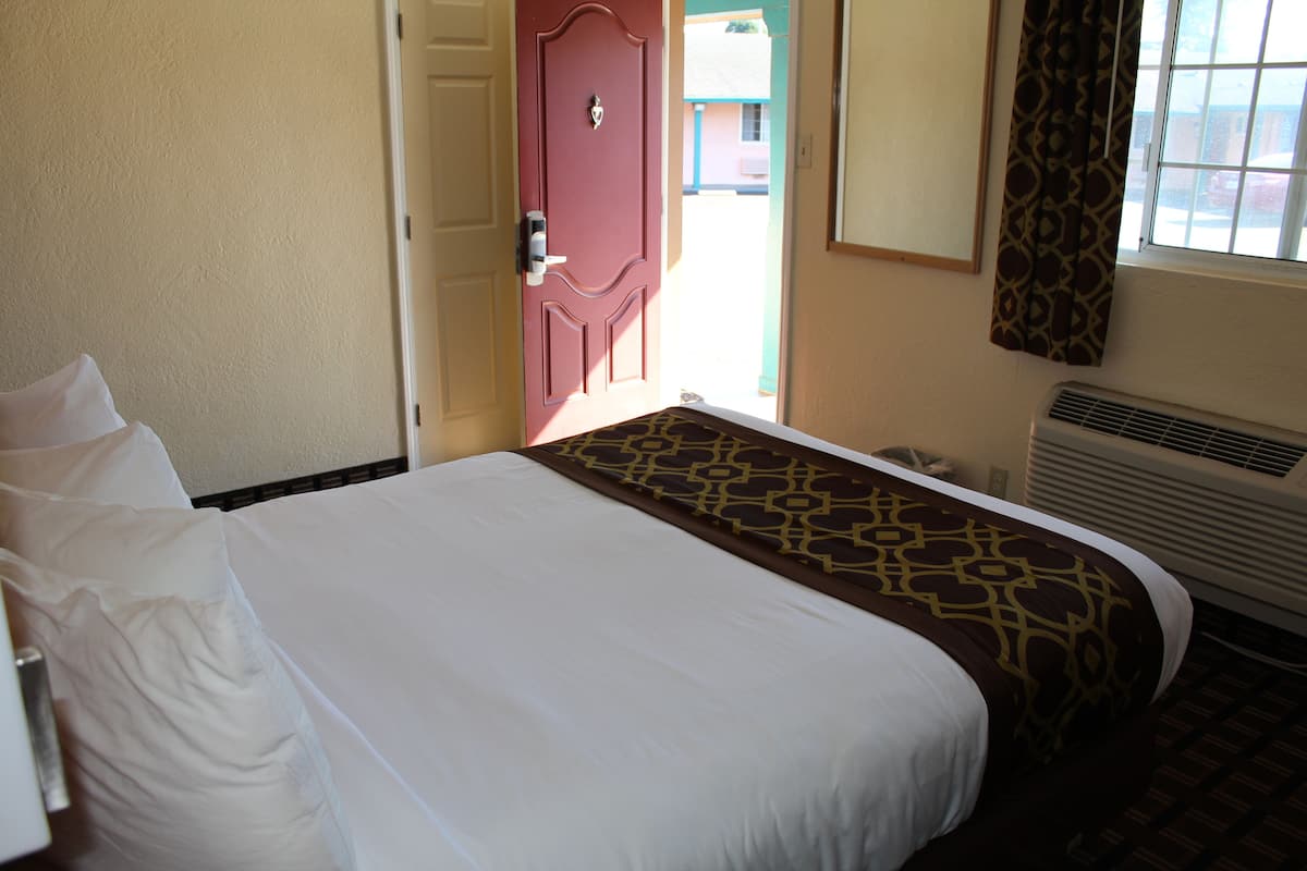 Quarto de hotel com uma cama, uma porta e uma janela.