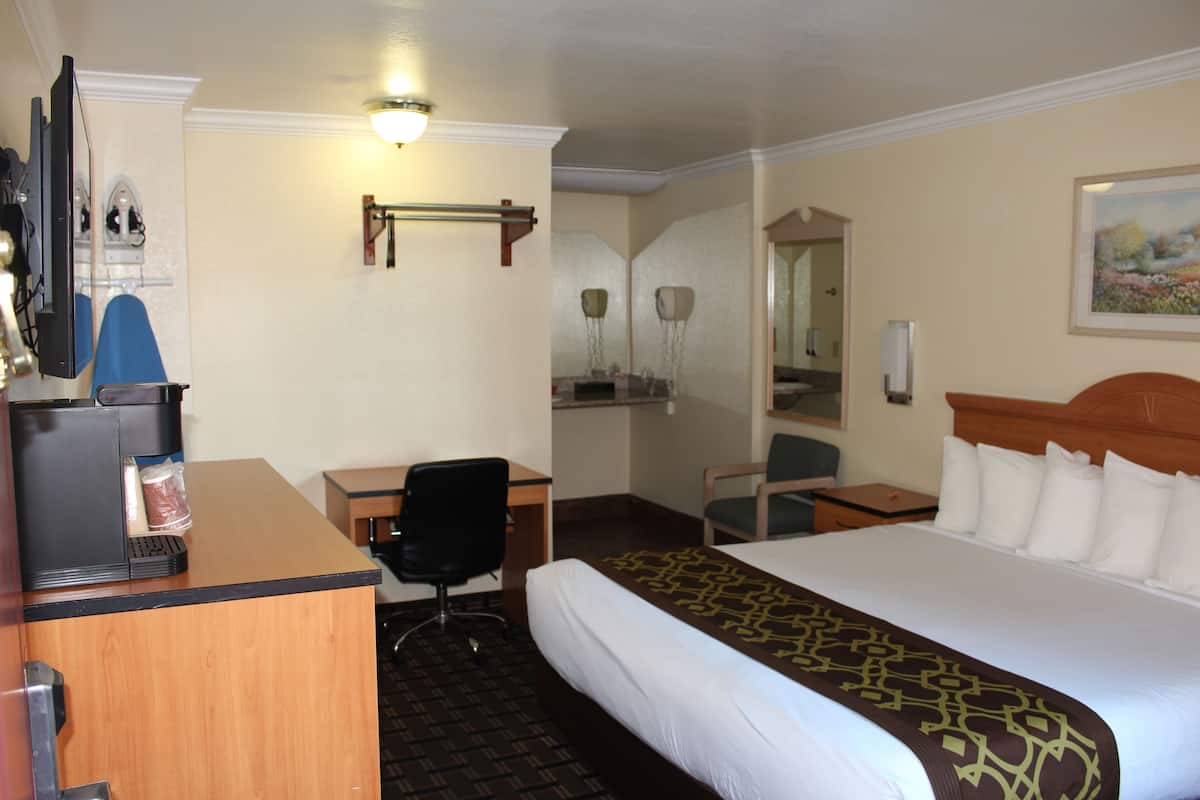 Quarto de hotel com cama, escrivaninha, cadeira e máquina de café.