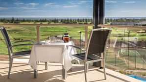 Varanda com mesa e cadeiras, vista para um campo de golfe.