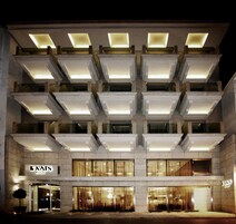Um hotel com fachada moderna, várias varandas e janelas iluminadas.