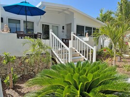 Uma casa moderna com fachada branca, uma parede de pedra e uma escadaria que leva a um deck.