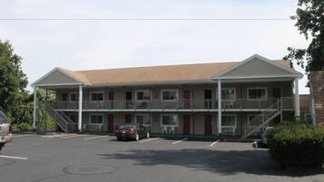 Um motel com estrutura em dois andares, área de estacionamento coberta e um pequeno espaço de estar ao ar livre.