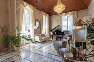 Uma sala de estar ampla com um piano de cauda, um candelabro e um vaso grande.